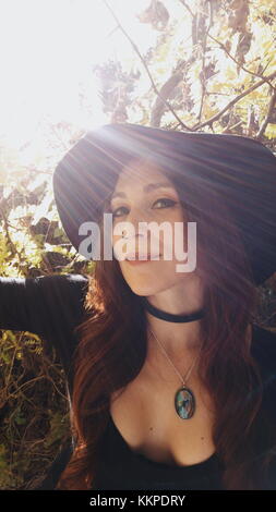 attractive woman in witch hat and wig holding magic wand in Halloween ...