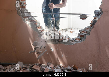 Man uses hammer smashed the walls of the house Stock Photo - Alamy
