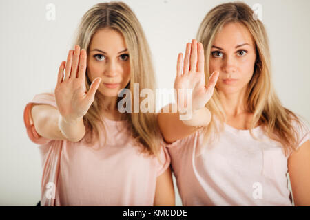 Twin sisters making stop sign over white background Stock Photo - Alamy