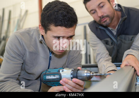 engineer showing apprentice how to use drill in factory Stock Photo - Alamy