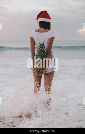Funny young woman in Santa hat with gingerbread cookie and glass of ...