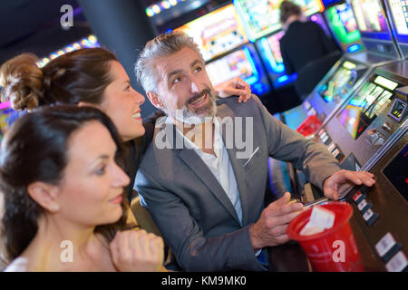 group of friends playing slot machines Stock Photo - Alamy