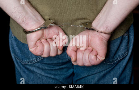 A mans hands in handcuffs behind his back Stock Photo - Alamy