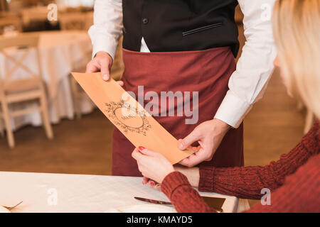 Waiter giving menu to client at restaurant Stock Photo - Alamy