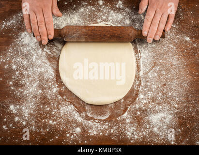 Hands with rolling-pin make dough for pizza. Italian pizza cooking ...