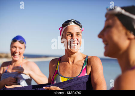 Laughing female open water swimmers wading in sunny ocean Stock Photo ...