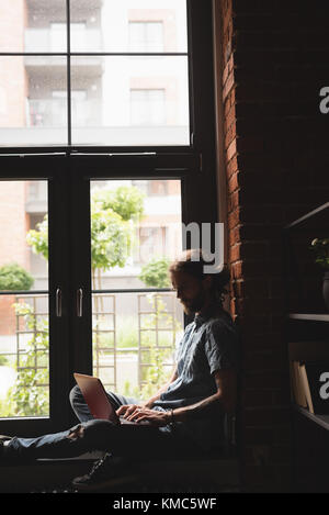 Man using laptop near window Stock Photo - Alamy