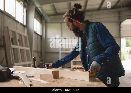 Carpenter measuring wooden slab with measuring tape Stock Photo - Alamy