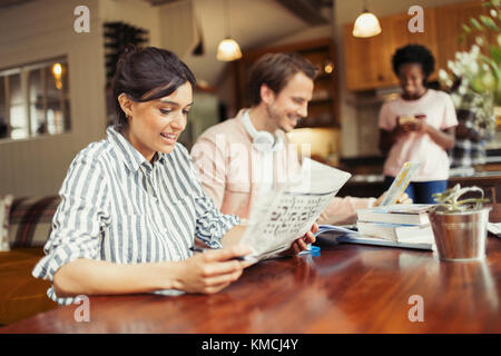 Adult man reading newspaper at dining table with his family sitting in ...