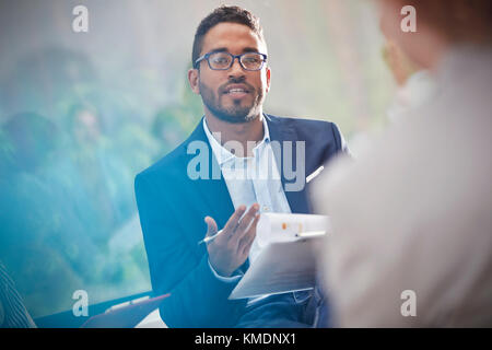 Young hispanic businessman holding clipboard sitting on the table at ...