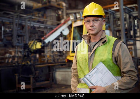 Portrait serious,confident steelworker with clipboard in steel mill ...
