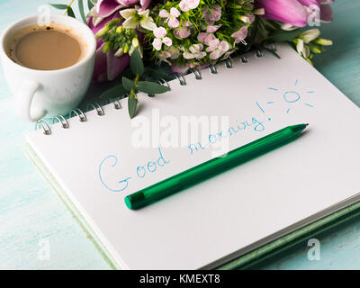 Rose flowers and good morning wish in notepad. Close up. White wooden ...