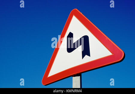 Double bend first to the left road sign. Crooked sign on crooked post ...