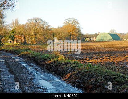 Ploughed field with trees and buildings of a village in the background ...