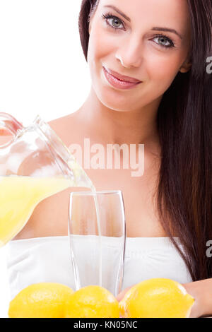 Beautiful young woman pouring lemon water into glass from jug in kitchen Stock Photo - Alamy