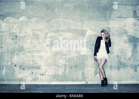 Young and beautiful woman leans against a colorful wall and poses for ...