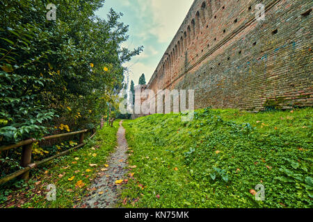 paved path near ancient walls of medieval castle in a green forest ...