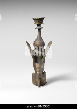 This bronze ornament depicts a seated male sphinx, a mythical creature ...