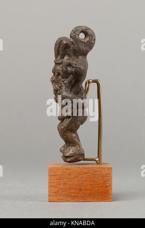 The image shows a sculpture of Bes, an ancient Egyptian deity, depicted ...