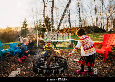 Three children standing around a fire near the jetty, evening, Lake ...
