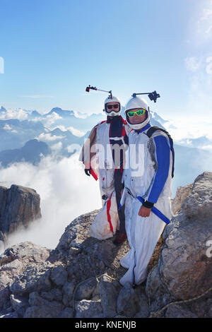 Two wingsuit BASE jumpers are flying very close over terrain. They ...