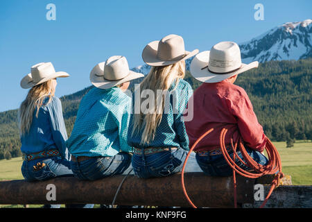 Cowboys sitting on fence Stock Photo - Alamy