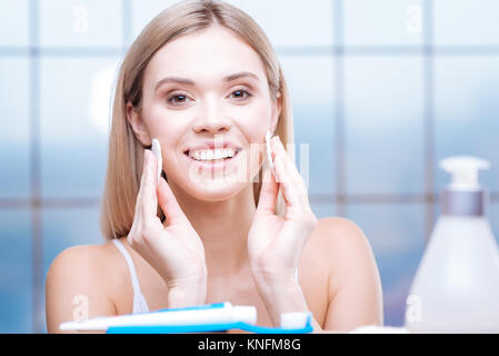 Cheerful woman removing makeup from her face. Beautiful brunette model ...