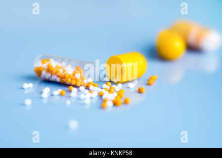 Close up split open medical pill capsule with spilled white powder on ...