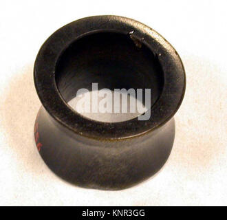 Ear spool made of metal, used as decorative jewelry, showing circular ...