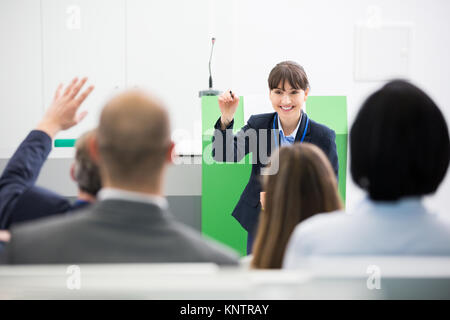 Smiling public speaker asking questions to audience during seminar ...