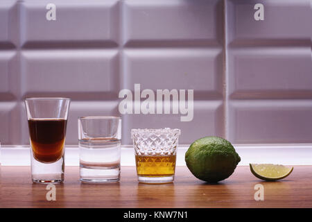Alcoholic strong drinks in piles on the background and pieces of lime ...