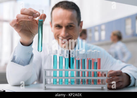 Scientist hand hold test tubes filled with blue sample chemicals in ...