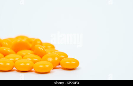 Yellow sugar coated tablets pills on white background with copy space ...