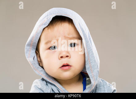 Little Asian Boy with angry confused expression on face sitting ...