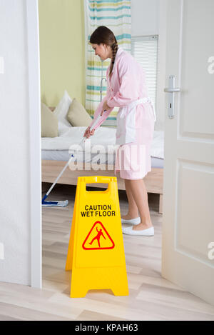 Young hotel maid cleaning floor with broom and dustpan. Housekeeping ...