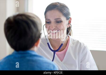 Nurse using stethoscope, smiling toward boy Stock Photo - Alamy