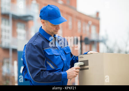 Delivery Man Standing And Scanning Cardboard Boxes With Barcode Scanner ...