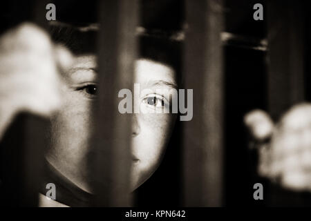 Confused child behind bars Stock Photo - Alamy