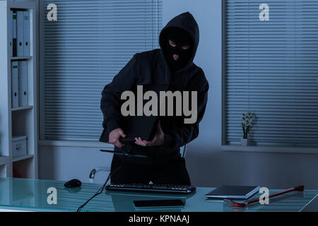 Male thief stealing computer monitor in room at night Stock Photo - Alamy