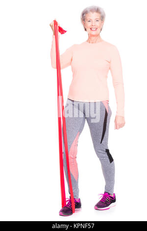Senior woman in a pink sporty long-sleeved top stretching her arms ...