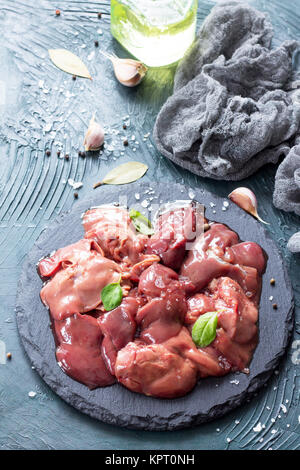 Raw chicken liver on a slate board and spices a gray stone background ...