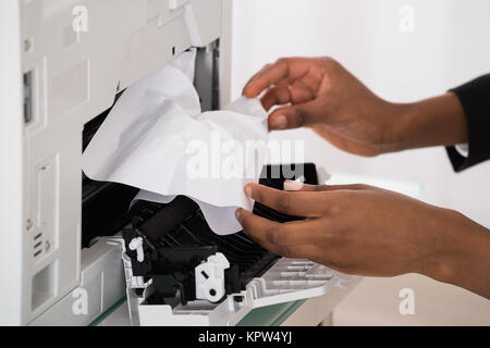 Businesswoman Removing Paper Stuck In Printer At Office Stock Photo - Alamy