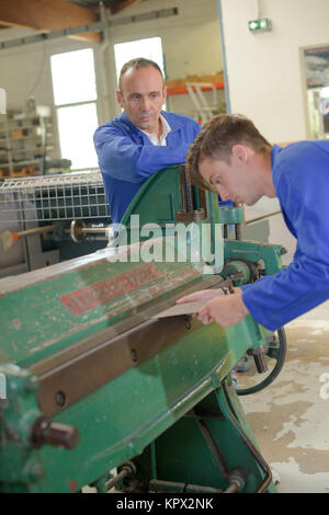engineer training male apprentice using a drill press Stock Photo - Alamy