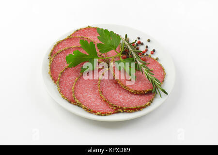 slices of green pepper coated salami with spices on white background ...