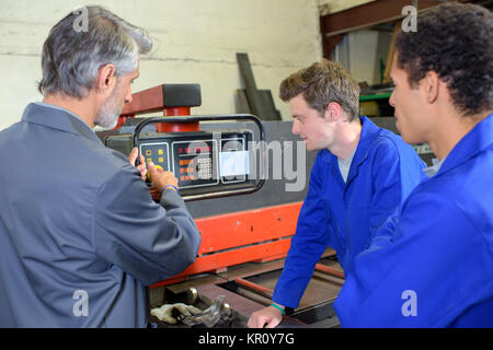 Man explaining workings of machine to two students Stock Photo - Alamy