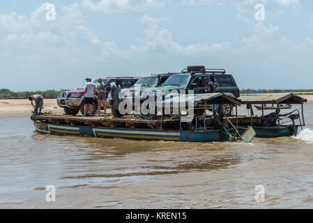 SUVs and passengers on board of ferry boat to cross Mania River ...