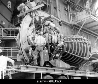 A Space Shuttle main engine is hoisted into a test stand for evaluation ...