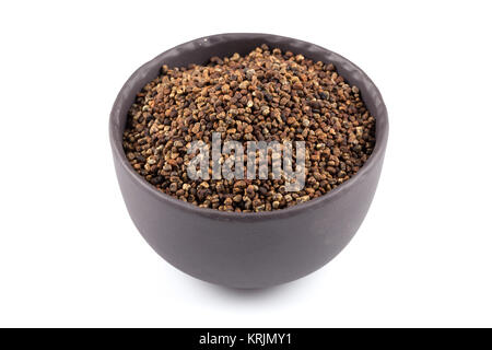Decorticated cardamom seeds in a dark stone bowl on white background ...