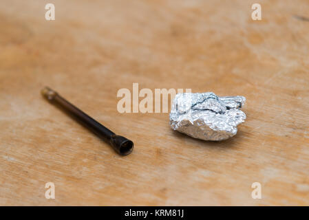 Marijuana in tin foil with pipe on wooden table Stock Photo - Alamy