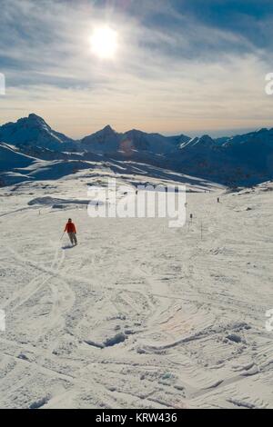 Steep ski slope and bright sun. Snowstorm on the surface. Skier rides ...